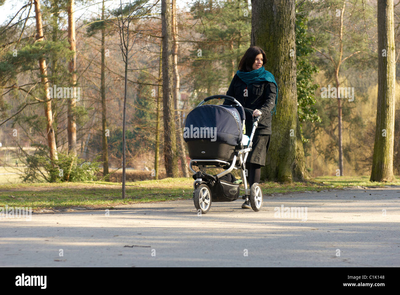 A mother with pushing pram on a bench, spring park Stock Photo - Alamy