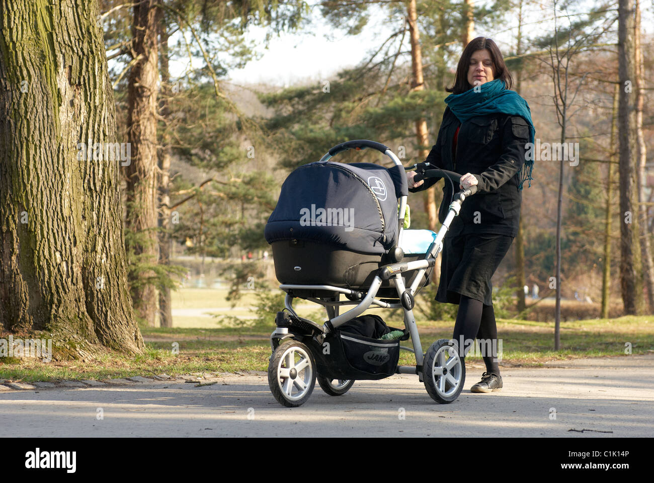 A mother with pushing pram on a bench, spring park Stock Photo - Alamy