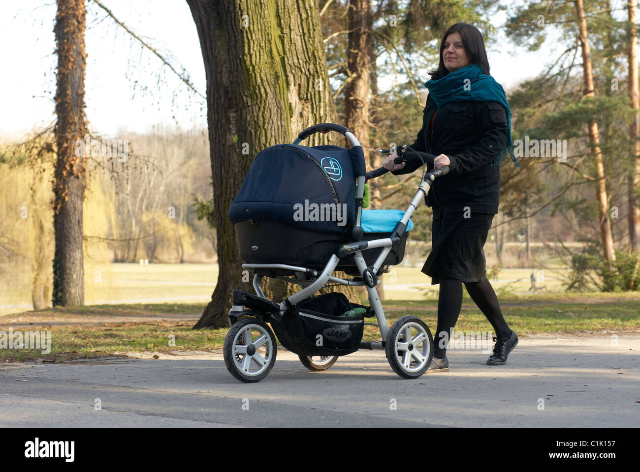 A mother with pushing pram on a bench, spring park Stock Photo - Alamy