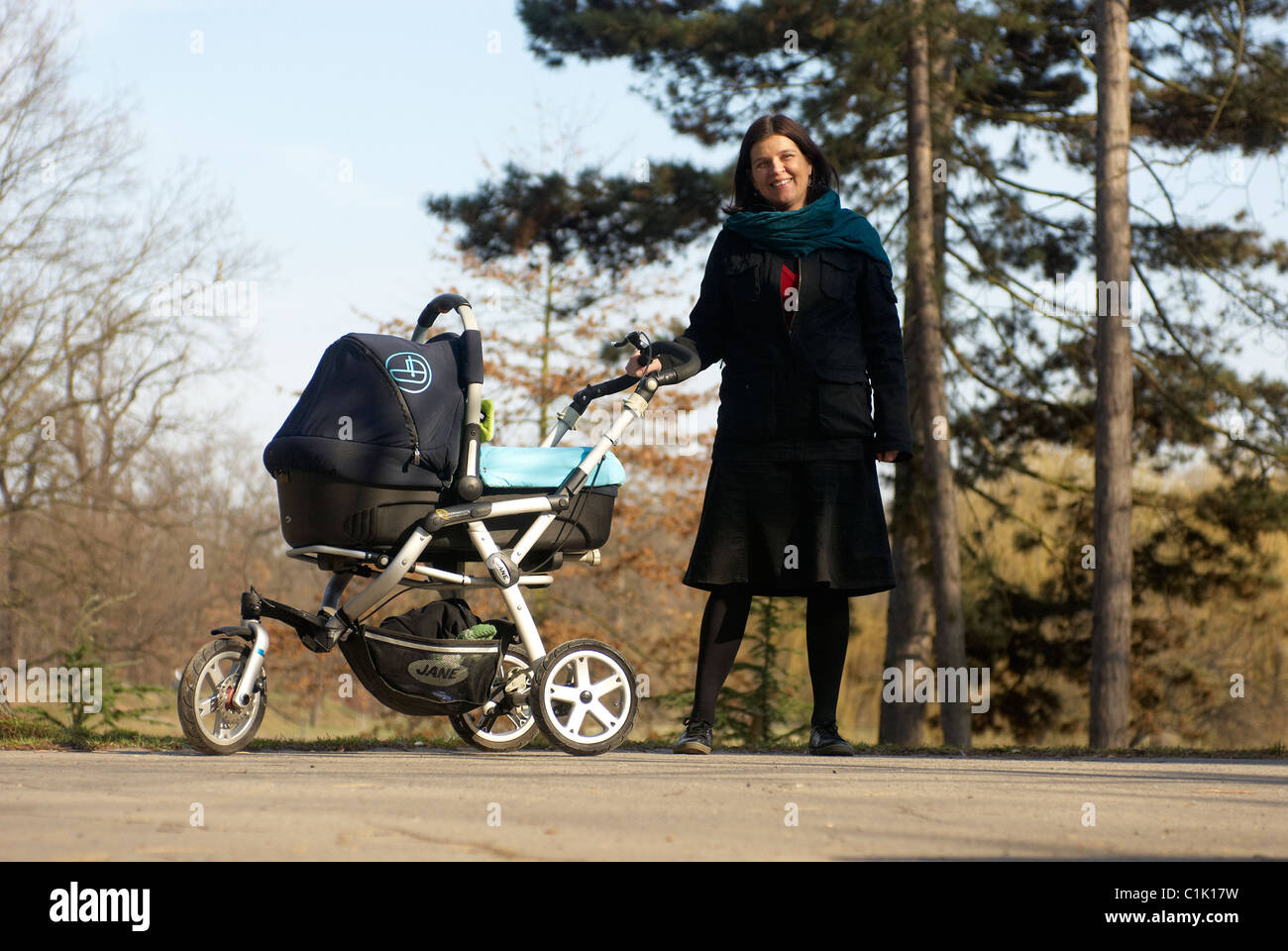 A mother with pushing pram on a bench, spring park Stock Photo - Alamy