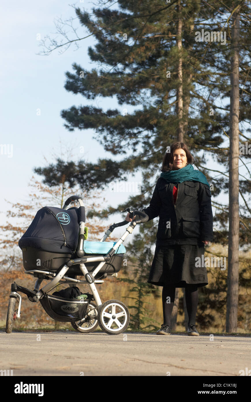 A mother with pushing pram on a bench, spring park Stock Photo - Alamy