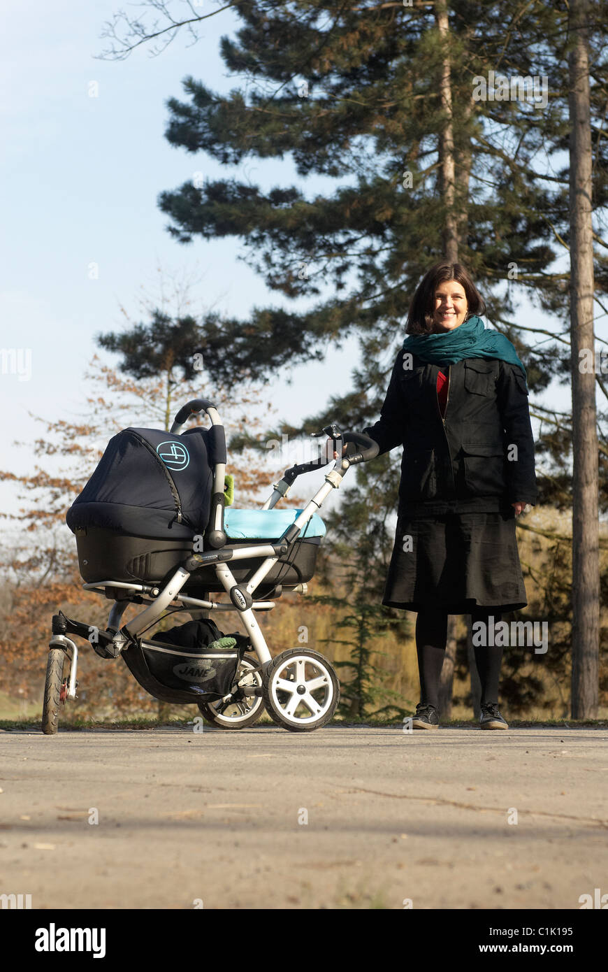 A mother with pushing pram on a bench, spring park Stock Photo - Alamy