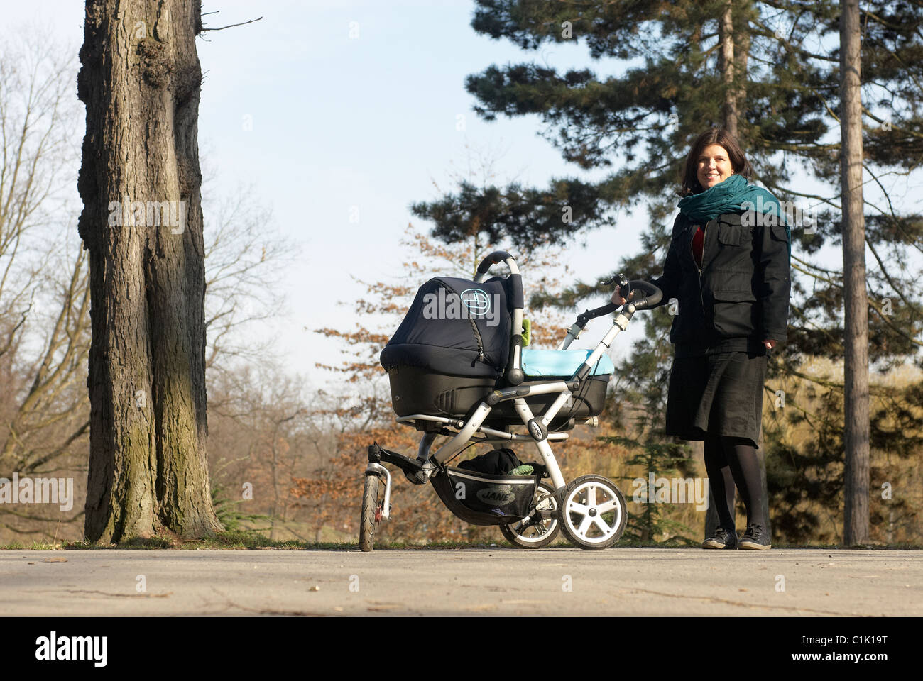 A mother with pushing pram on a bench, spring park Stock Photo - Alamy