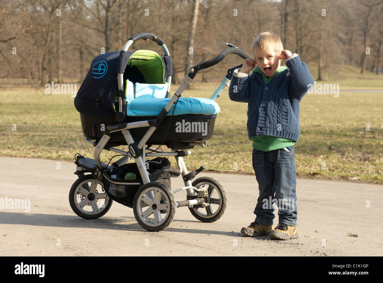Child blond boy pushing stroller with sister in park Stock Photo - Alamy