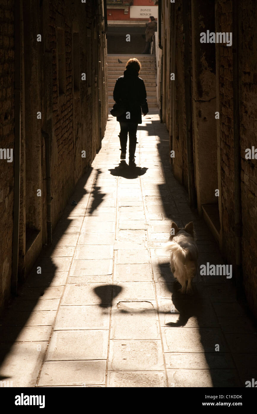 A woman walks her dog in the narrows streets of Venice, Italy Stock ...
