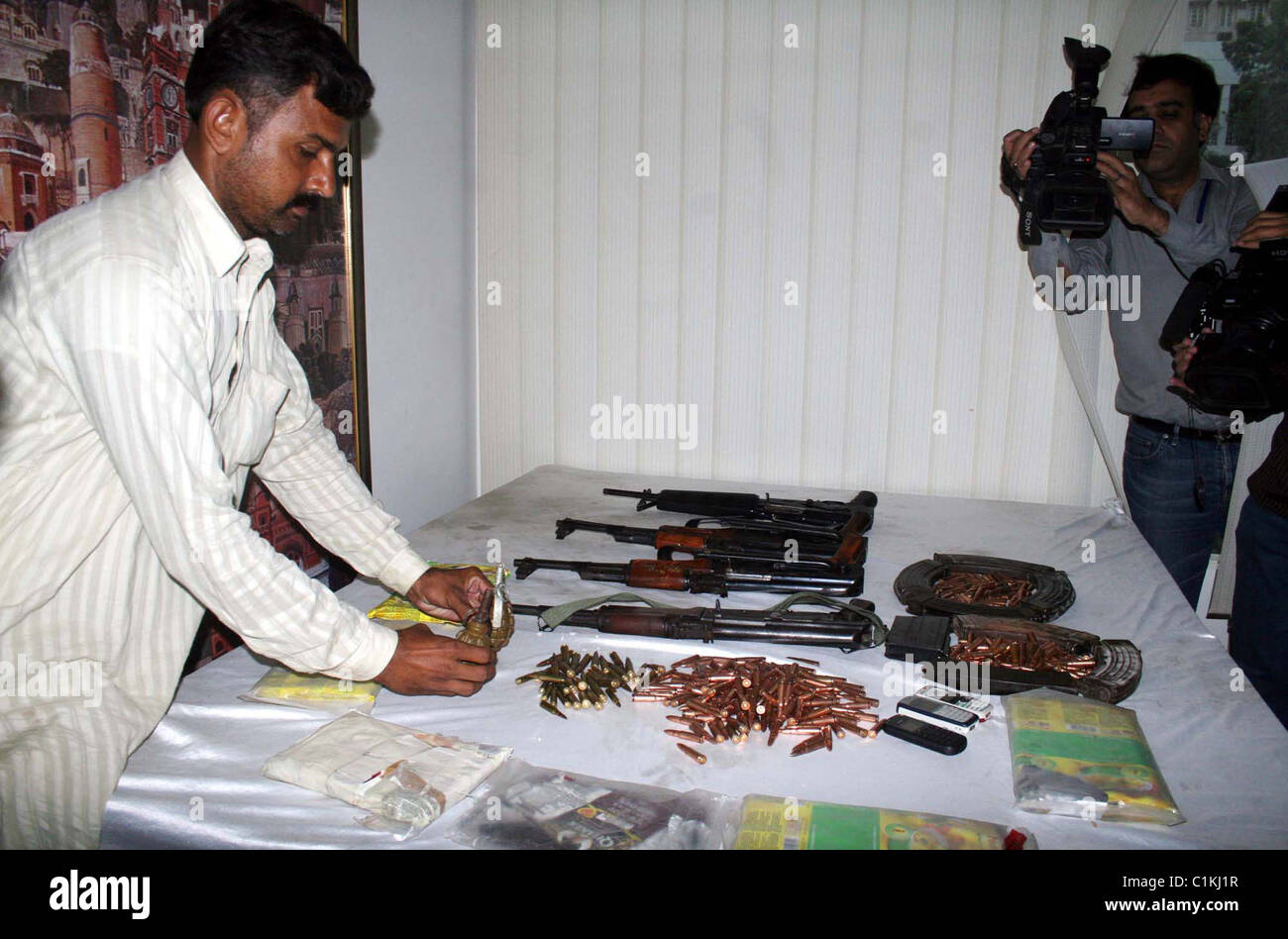 Plain-cloth policeman shows seized hand-grenades, weapons, bullets ...