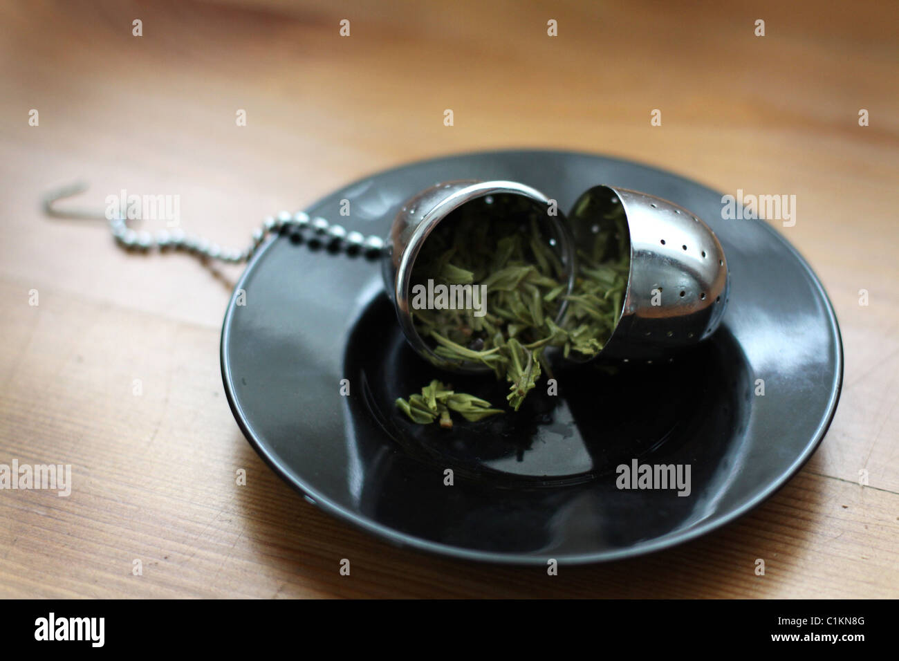 A tea ball open and showing green tea leaves Stock Photo - Alamy