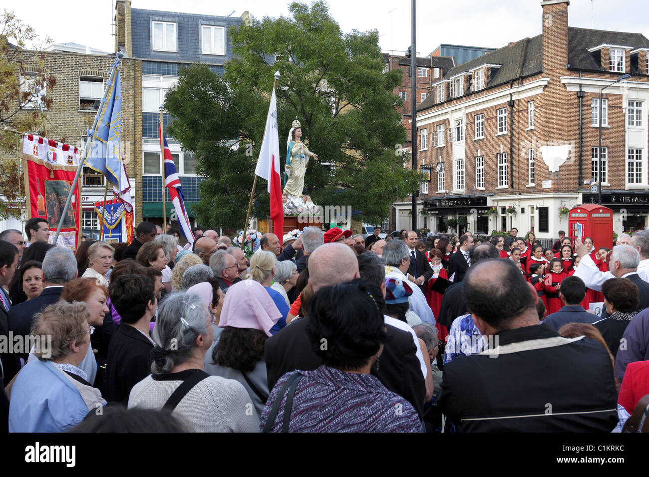 Maltese ex-pats crowd around an raised Madonna held aloft by ...