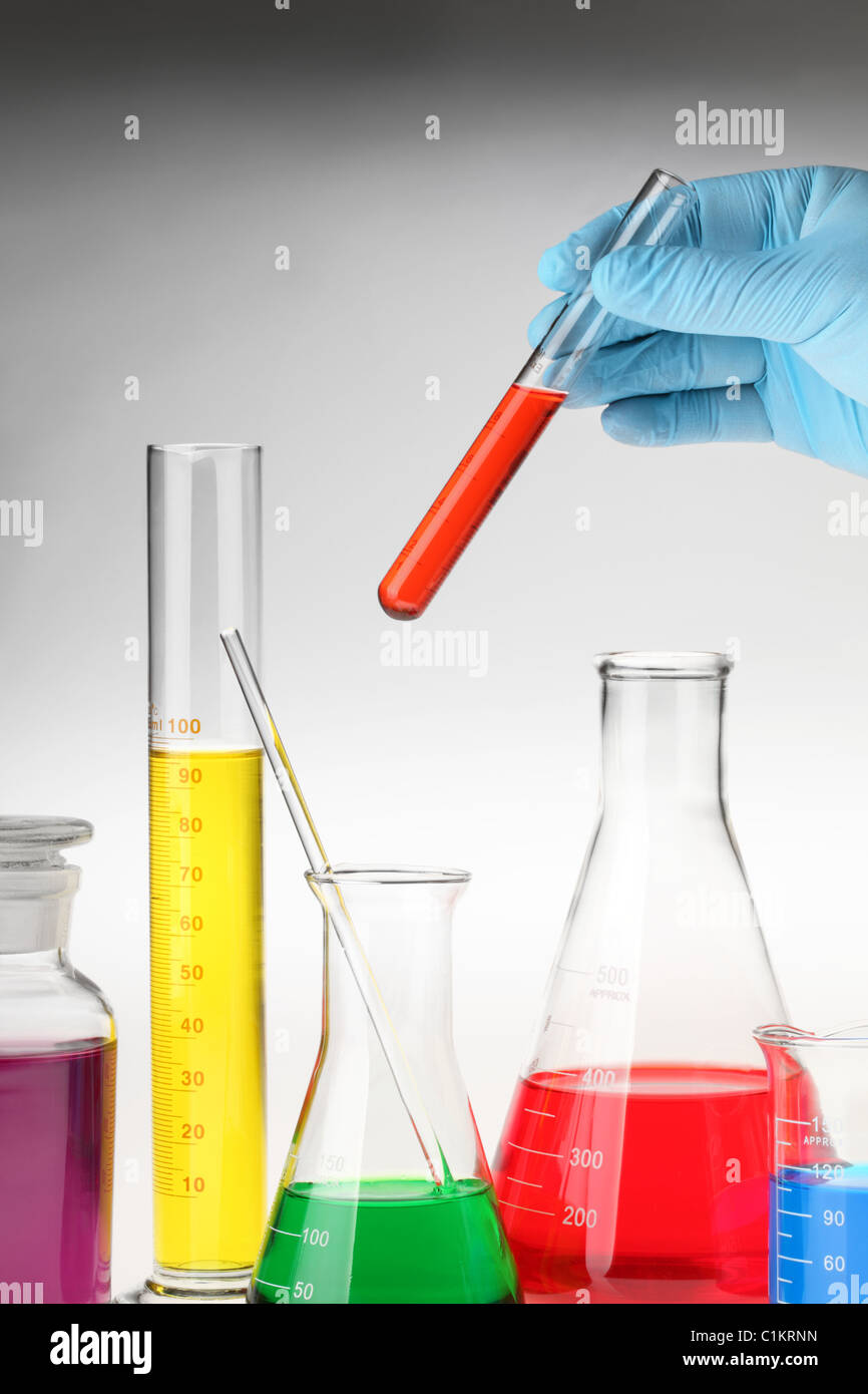 Hand holding test-tube among lab glassware Stock Photo - Alamy