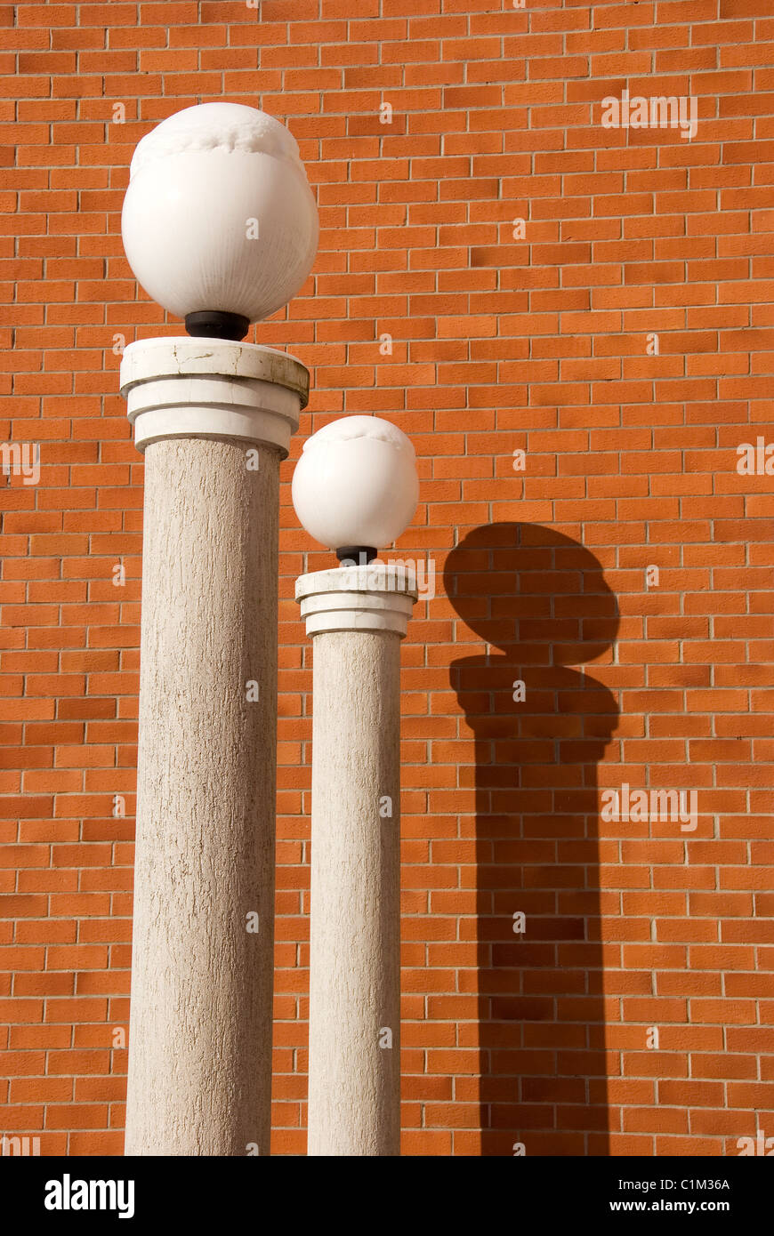 lamps on two white columns and shadow on red brick wall Stock Photo - Alamy