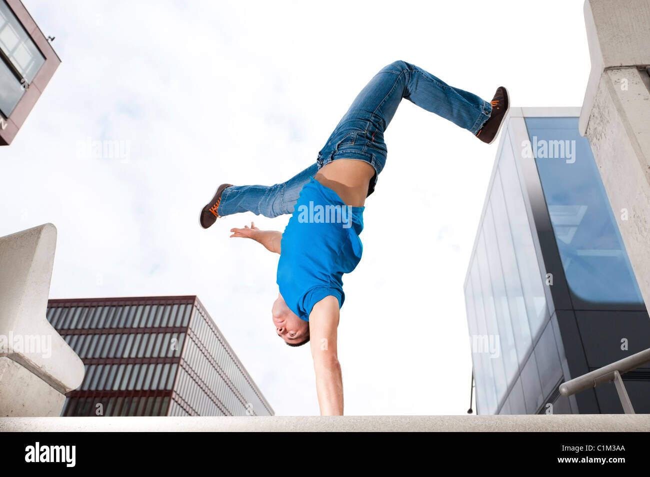 Jumping young man in front of buildings Stock Photo - Alamy
