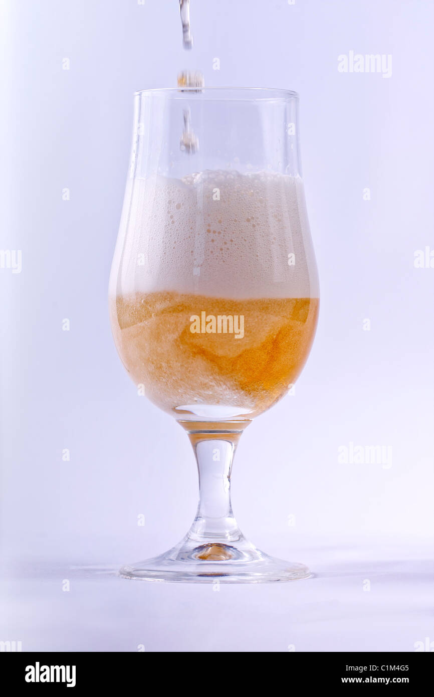Close view of a glass being filled with beer isolated on a white ...