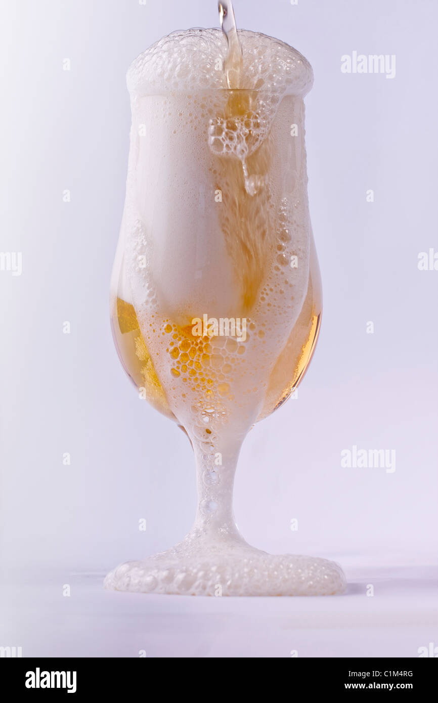 Close view of a glass being filled with beer isolated on a white ...