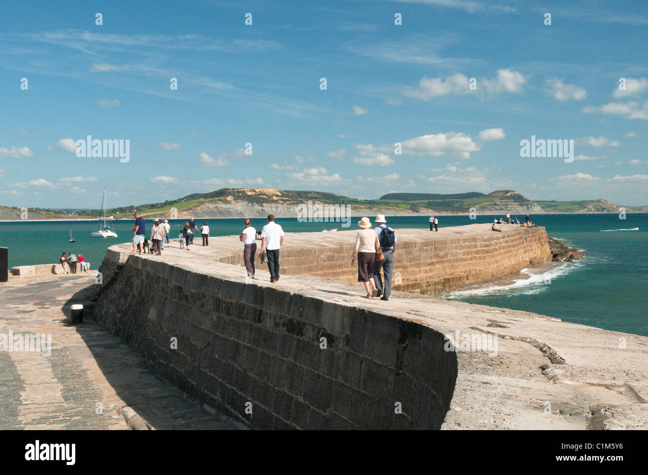 People walking on the top of The Cobb, ancient harbour wall, Lyme Regis ...