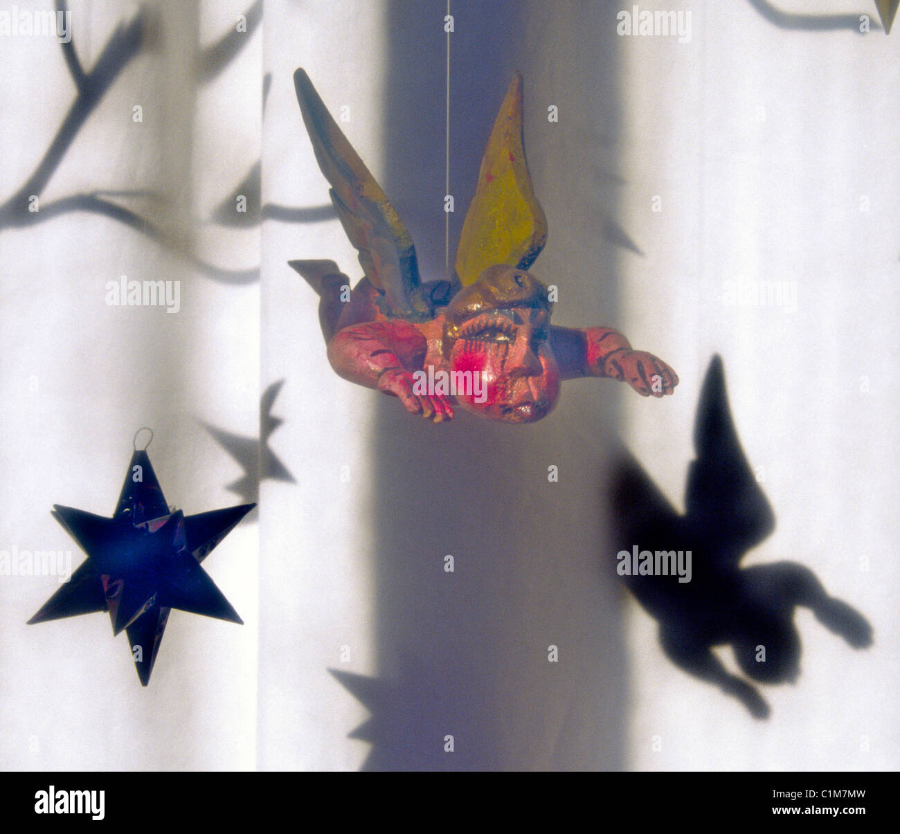 A pudgy, flying angel Christmas ornament casts his shadow in an art ...