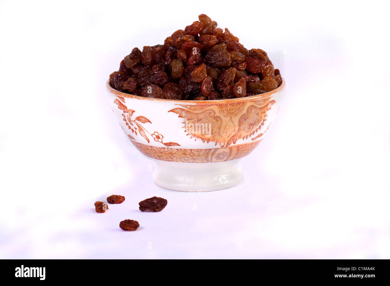 Close view of a bowl filled with dry raisins isolated on a white ...