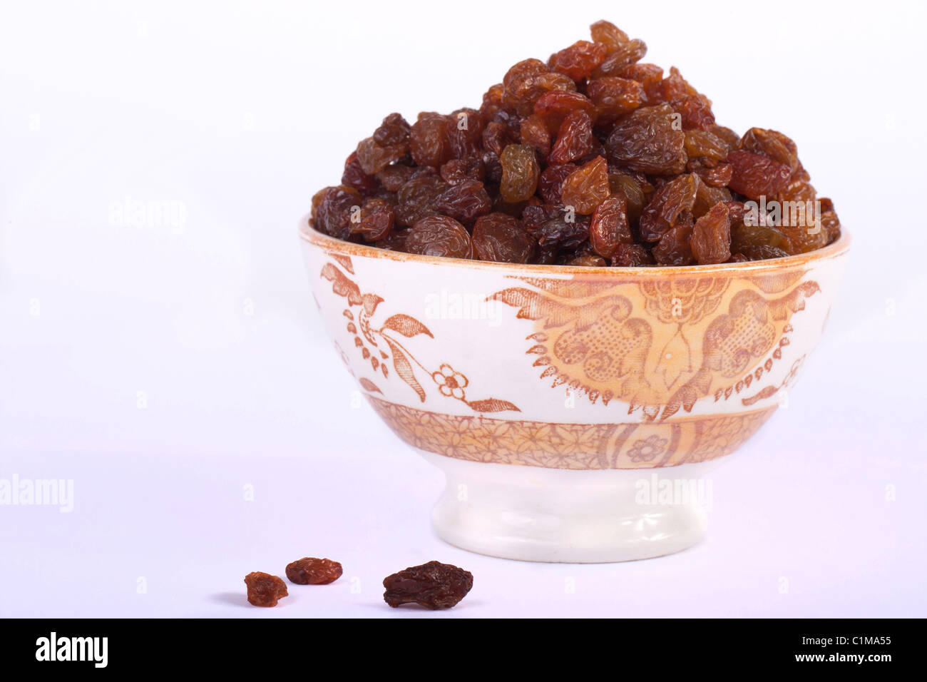 Close view of a bowl filled with dry raisins isolated on a white ...