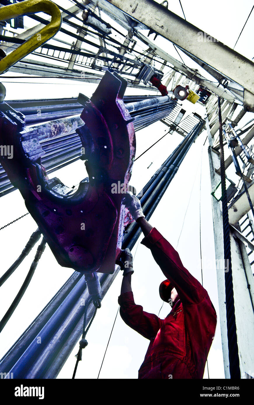 Low angle view of derrick with oil field services worker using power ...