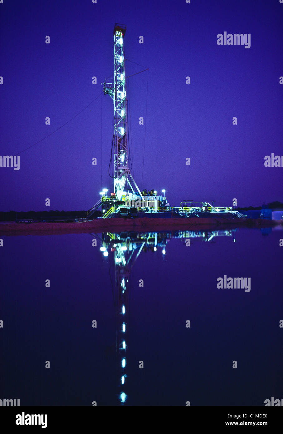 Illuminated oil rig at night reflected in water Stock Photo - Alamy