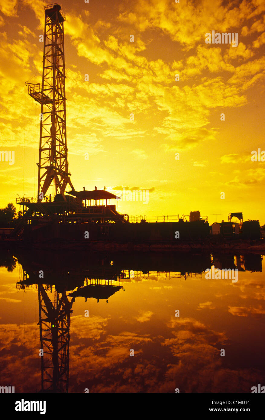 Oil rig at sunset reflected in water Stock Photo - Alamy