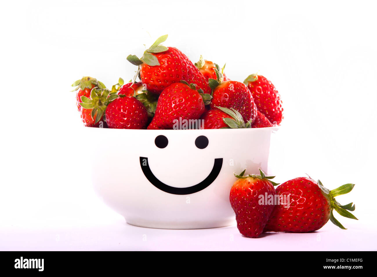 View of a smiley bowl filled with strawberries isolated on a white ...