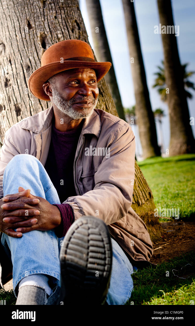 An elderly man sitting against a tree thinking about his day Stock ...