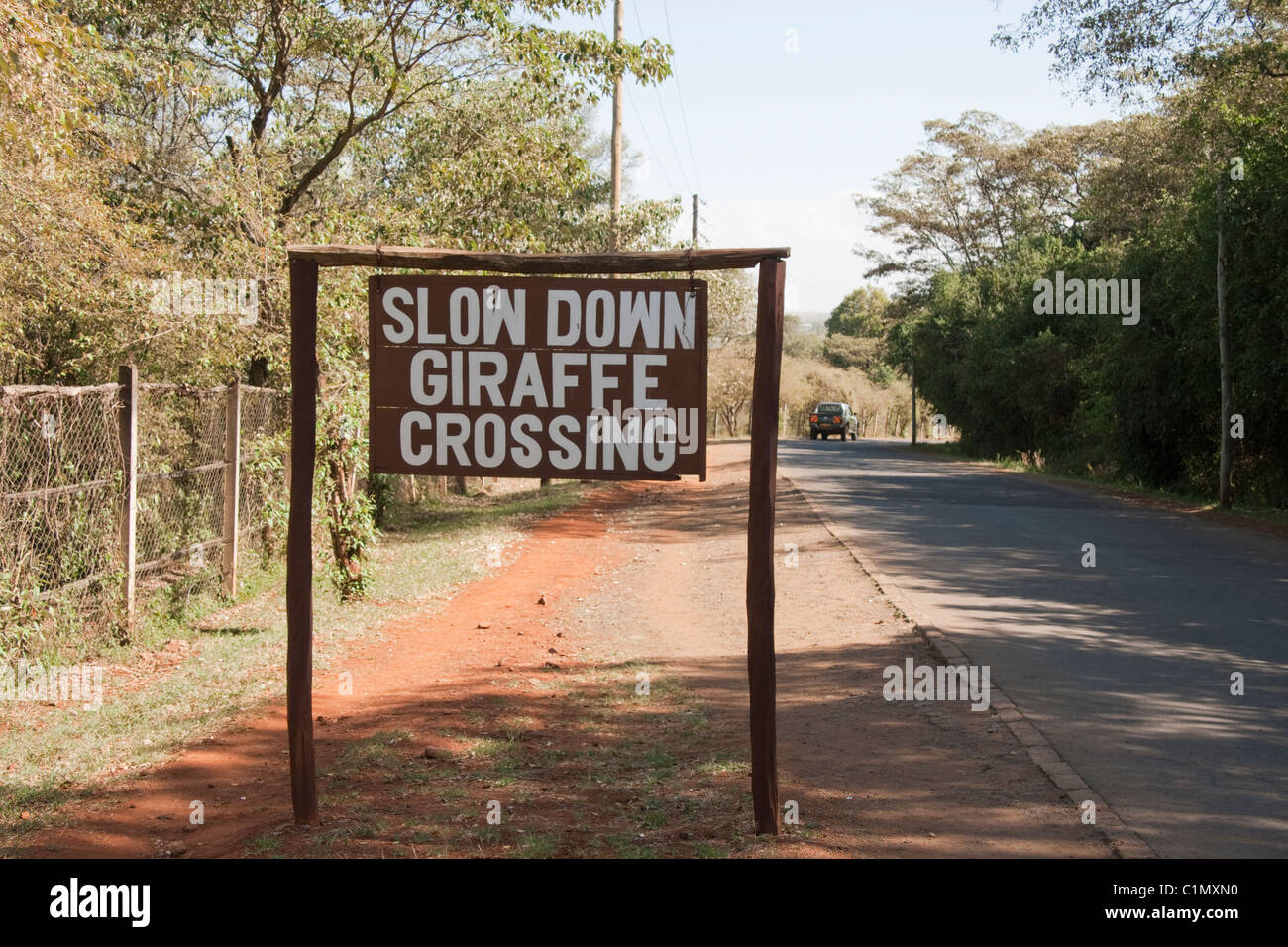 A sign in Kenya reads Slow Down Giraffe Crossing Stock Photo - Alamy