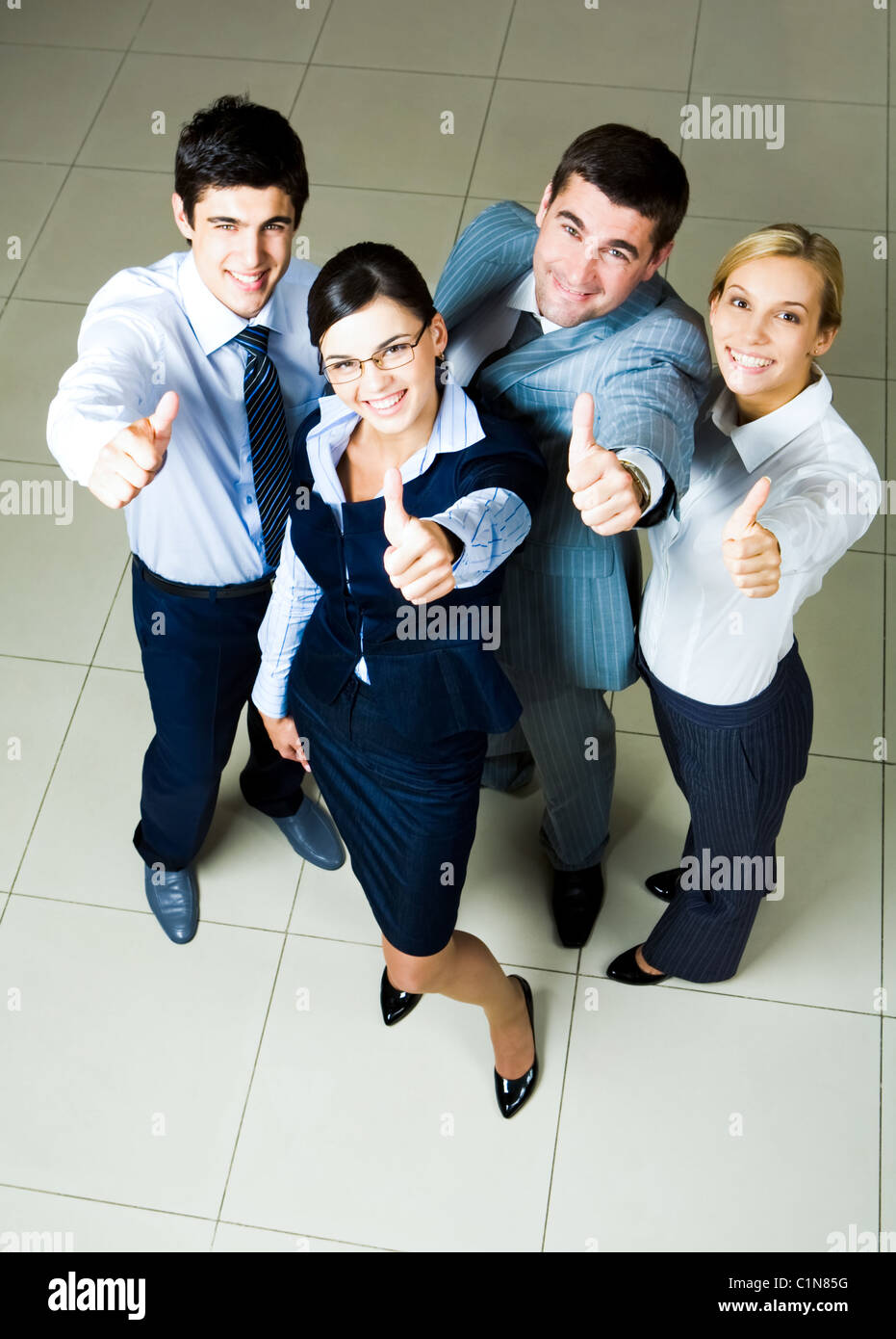 Image of four successful employees smiling at camera and showing thumbs ...