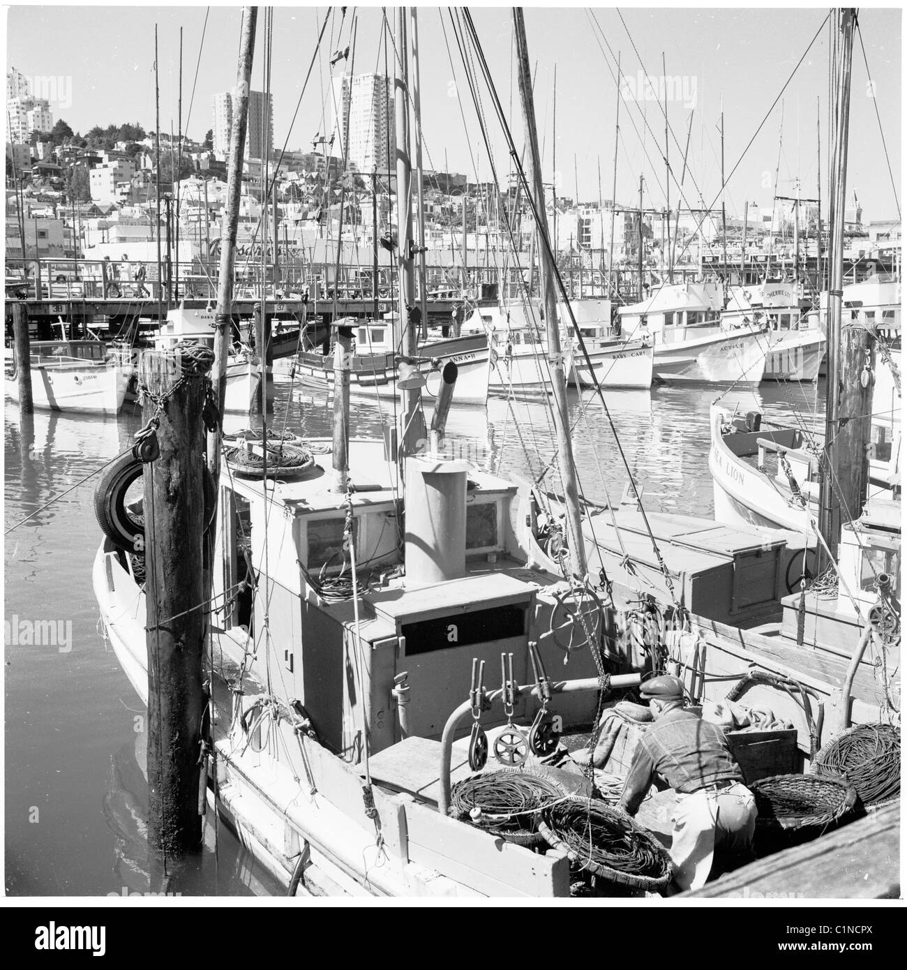 America, 1950s. Wooden fishing boat in harbour with skipper checking ...