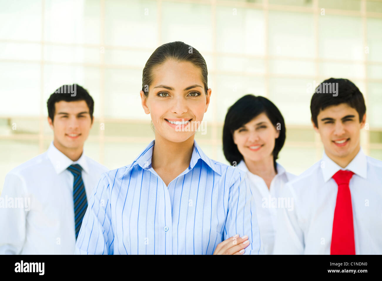 Portrait of pretty employee smiling at camera with business partners at ...