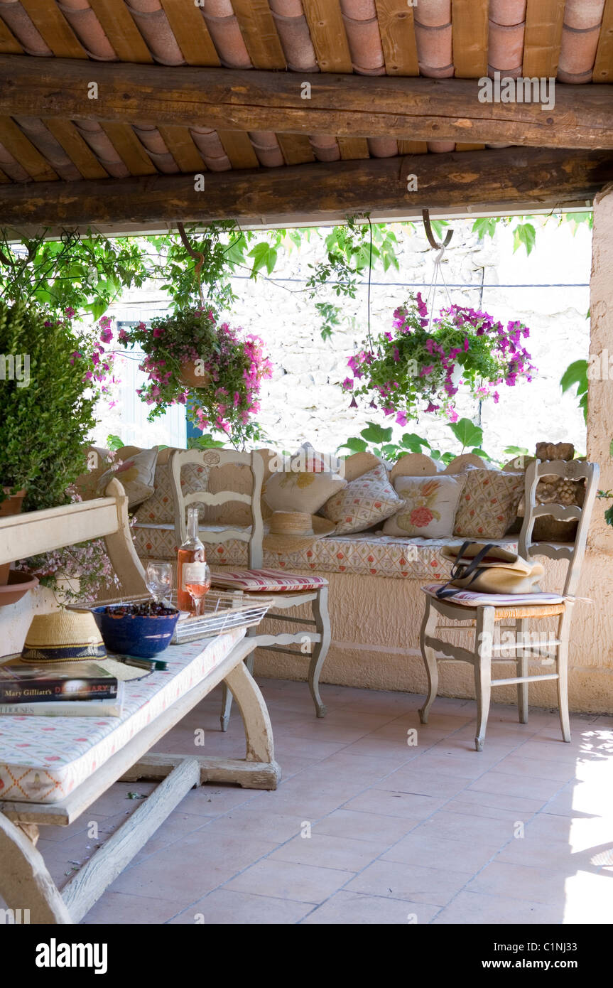 Covered terrace area with wooden bench and Provencal chairs Stock Photo ...