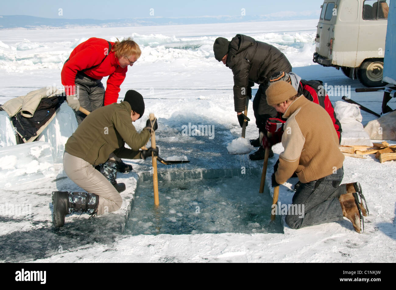 Man sawing an ice hole for ice-diving, in lake Baikal, Siberia, Russia ...