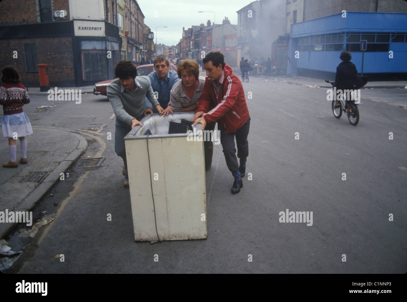 Toxteth Riot 1980s UK. Men looting pushing sink unit down the main ...