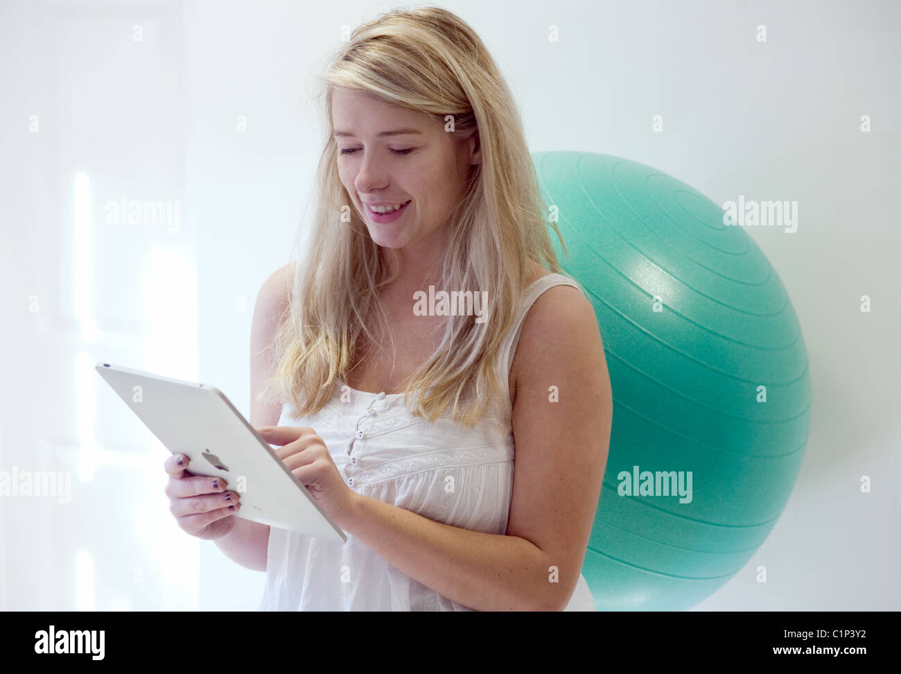 Teenage girl using iPad while using a pilates ball, UK Stock Photo - Alamy