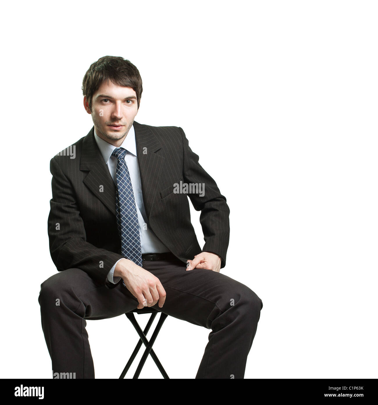 Confident businessman sitting on chair over white Stock Photo - Alamy