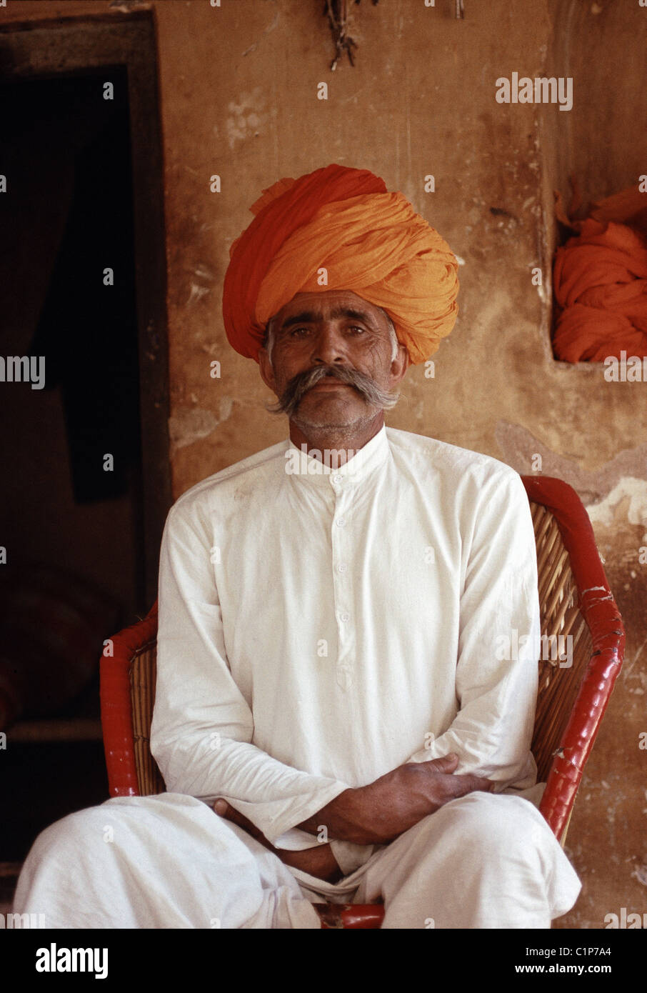 A turbaned man in Rajasthan, India sits on his front porch. A ...