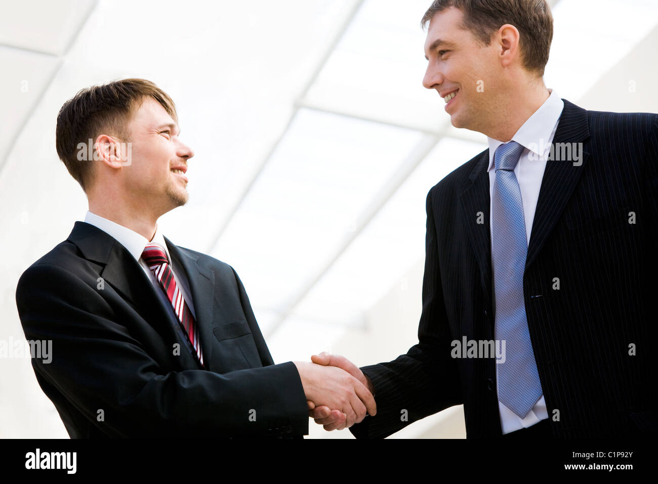 Portrait of two happy businessmen handshaking after striking promising ...