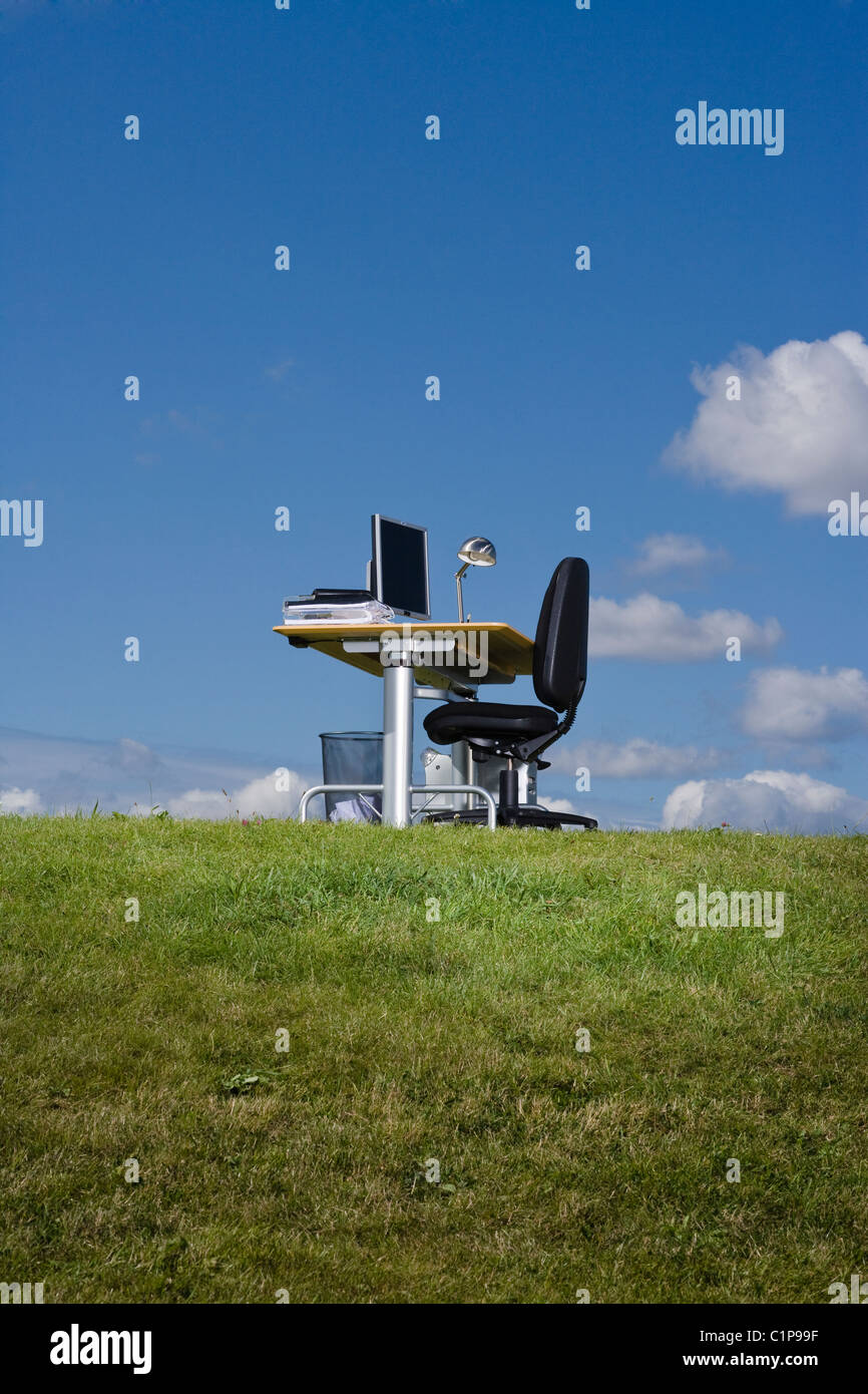 Office desk in grass field against blue sky Stock Photo - Alamy