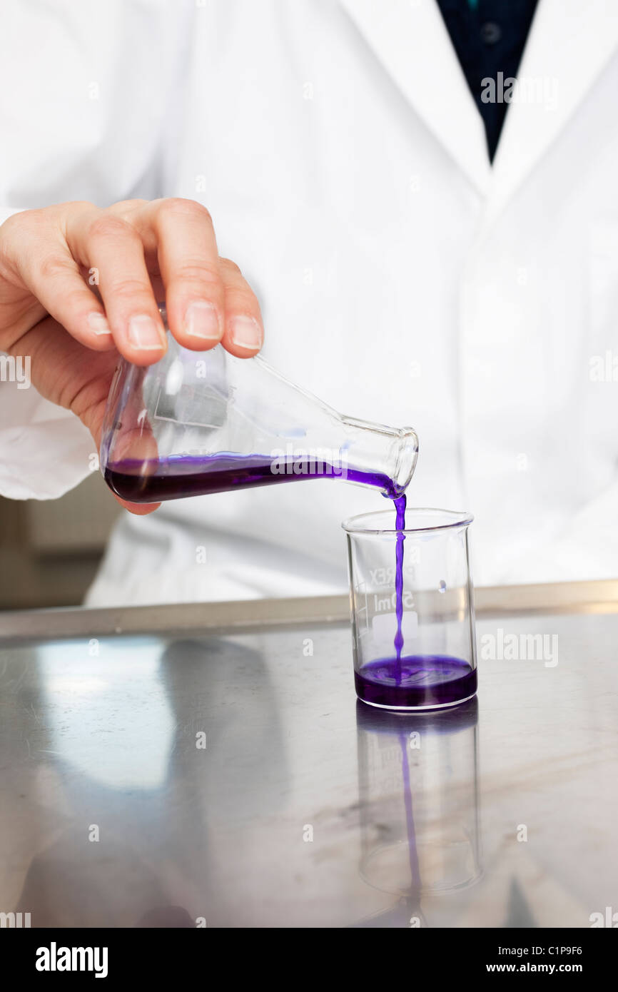 Scientist pouring liquid from beaker Stock Photo - Alamy