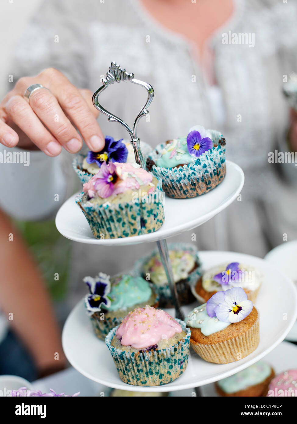 Hand reaching for muffins decorated with fresh flowers Stock Photo - Alamy