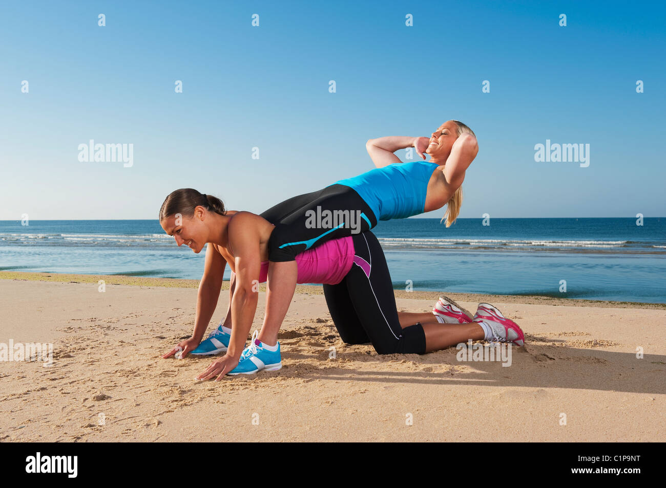Two women exercising together on beach Stock Photo - Alamy