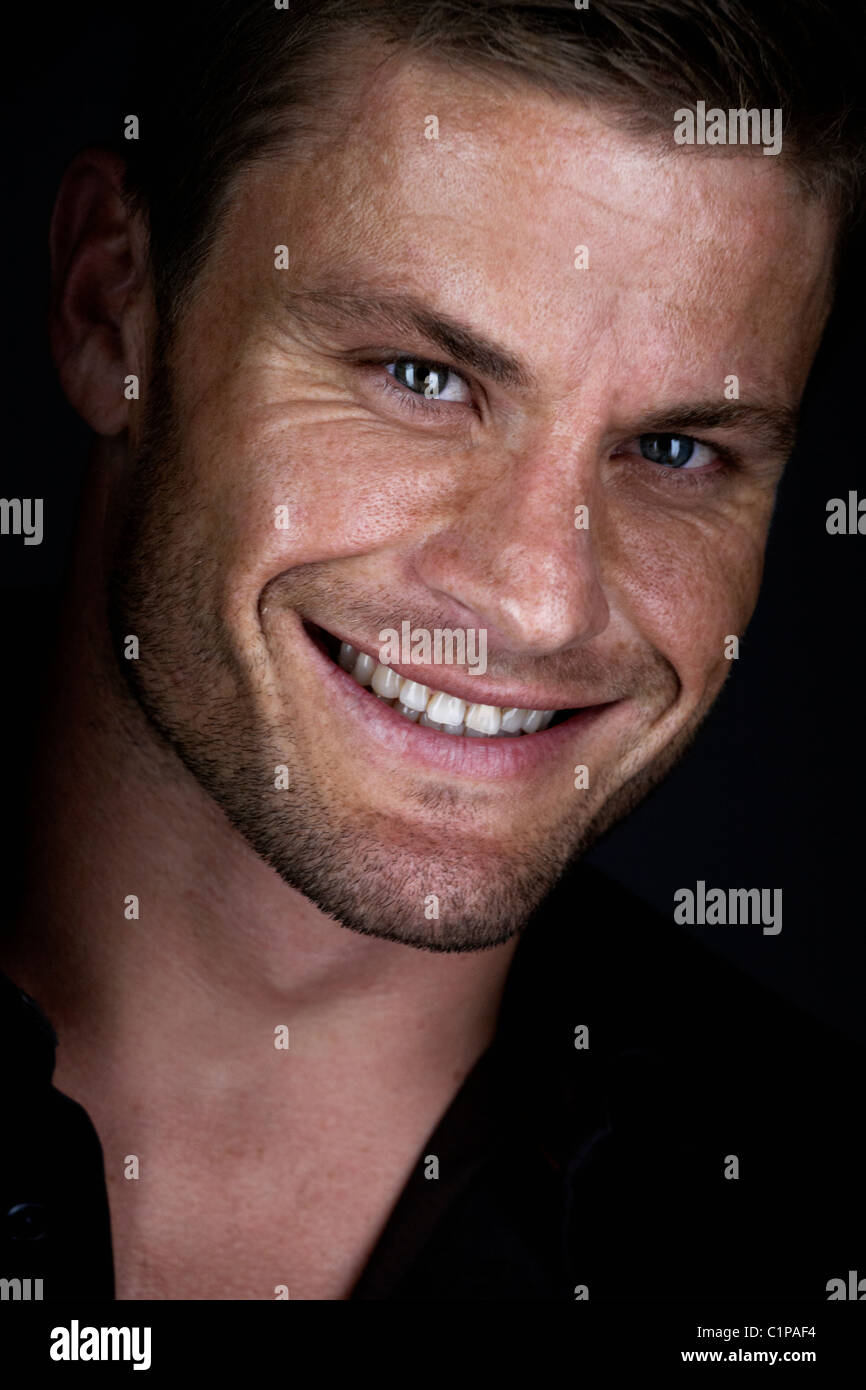 Portrait of smiling man against black background Stock Photo - Alamy