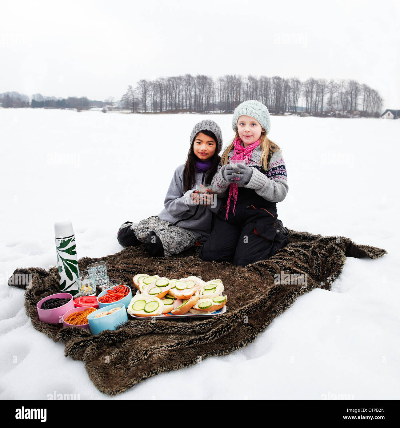 Portrait of two girls having picnic in snow Stock Photo - Alamy