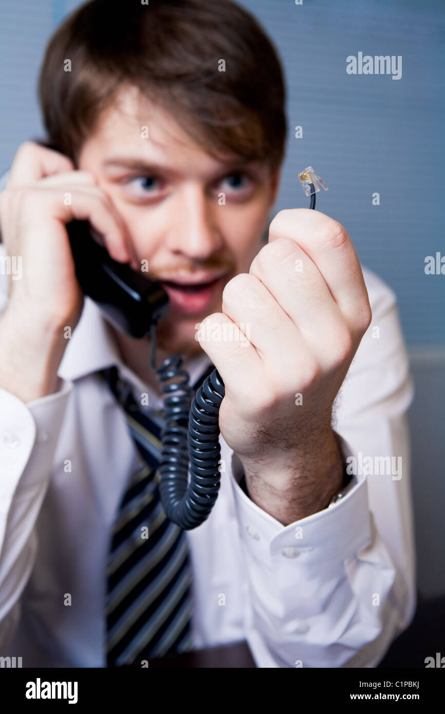 Photo of troubled man looking at disconnected telephone hub in his hand ...