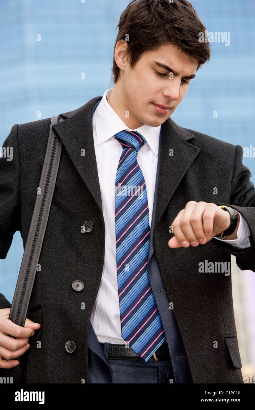 Portrait of worried manager looking at watch with serious expression ...