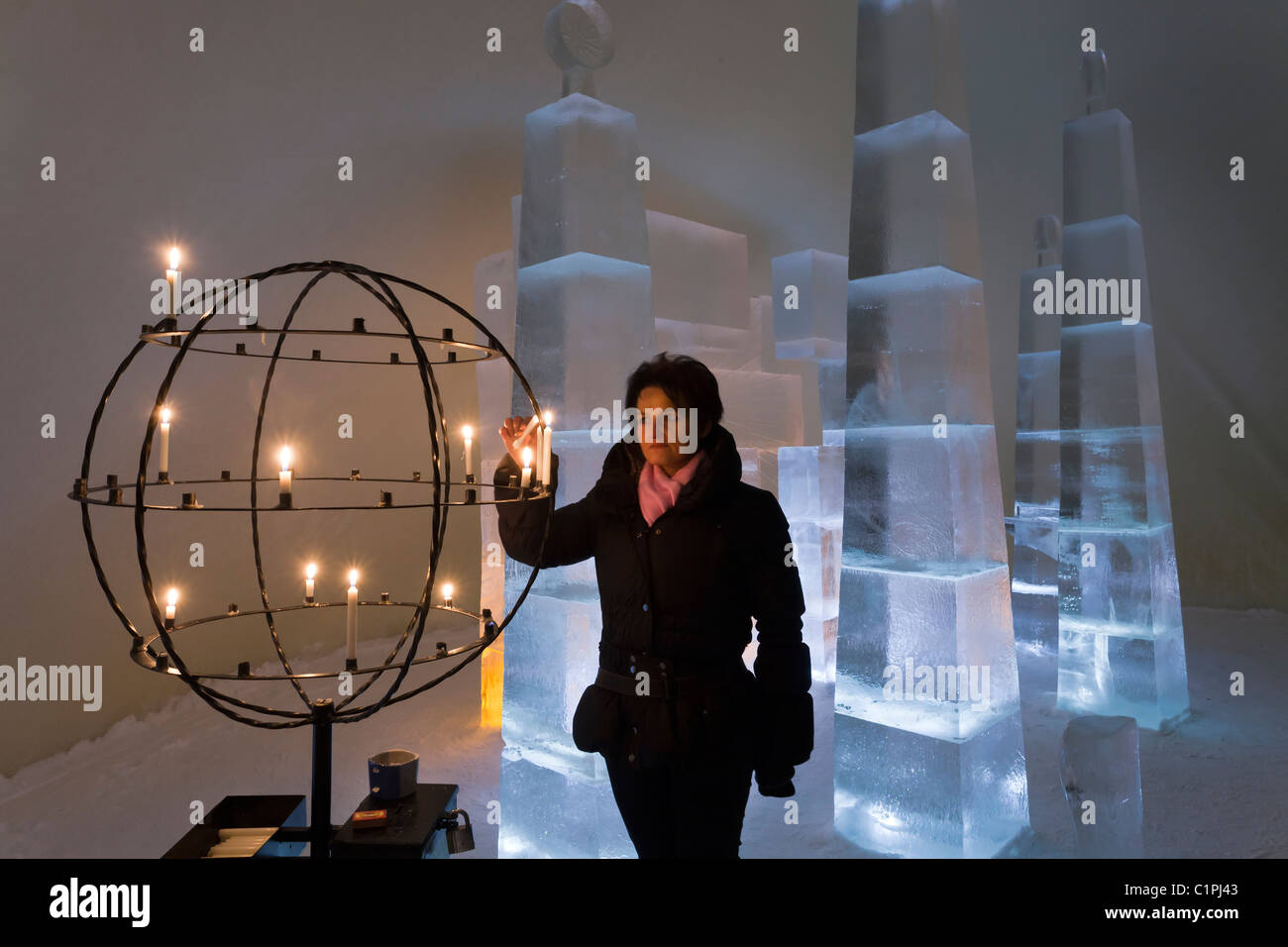 A woman is lighting the candle in candelabrum, in the ice church ...