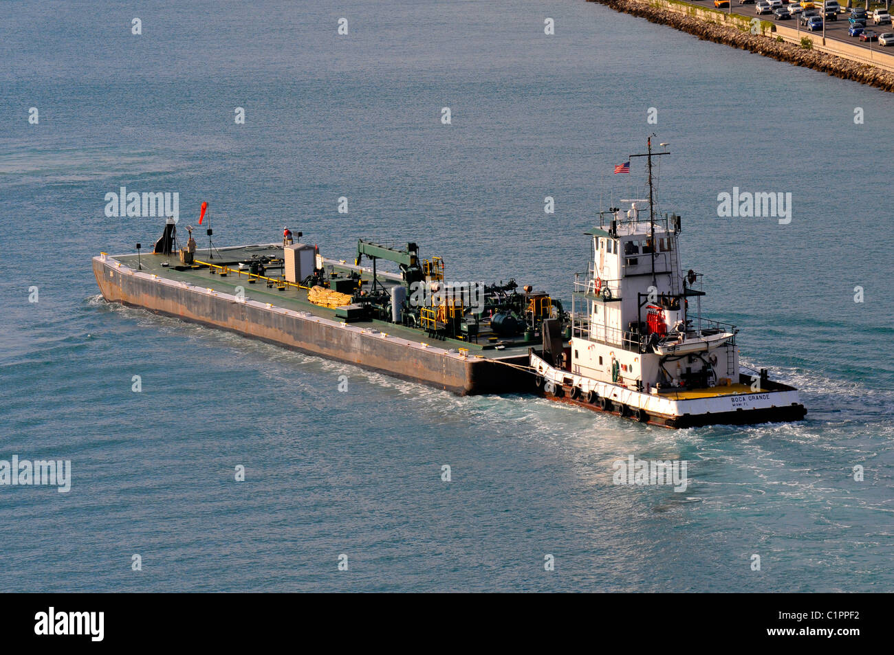 Tug boat moving barge in Miami Florida harbor Stock Photo - Alamy