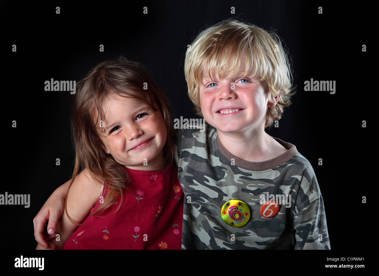 A young boy and girl celebrate the older boys sixth birthday and pose ...