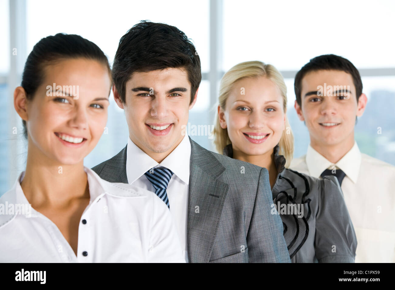 Handsome boss looking at camera with smile surrounded by employees ...