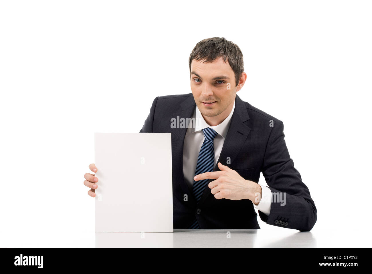 Image of successful male pointing at blank paper and looking at camera ...